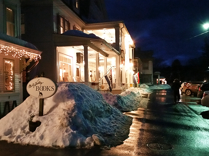 The bookstore after dark, glowing like a literary lighthouse, beckoning bibliophiles through snowdrifts with promises of literary treasures inside.