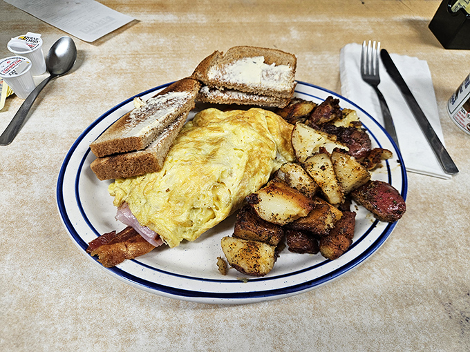 This hearty breakfast plate showcases the diner's perfect execution of classics &ndash; a fluffy omelet, crispy home fries, and toast ready for slathering with butter.