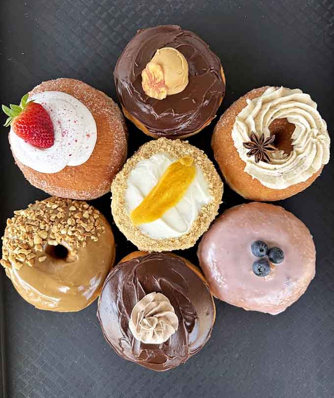 This rainbow of glazed perfection looks like happiness arranged in a circle, each one a small edible masterpiece.