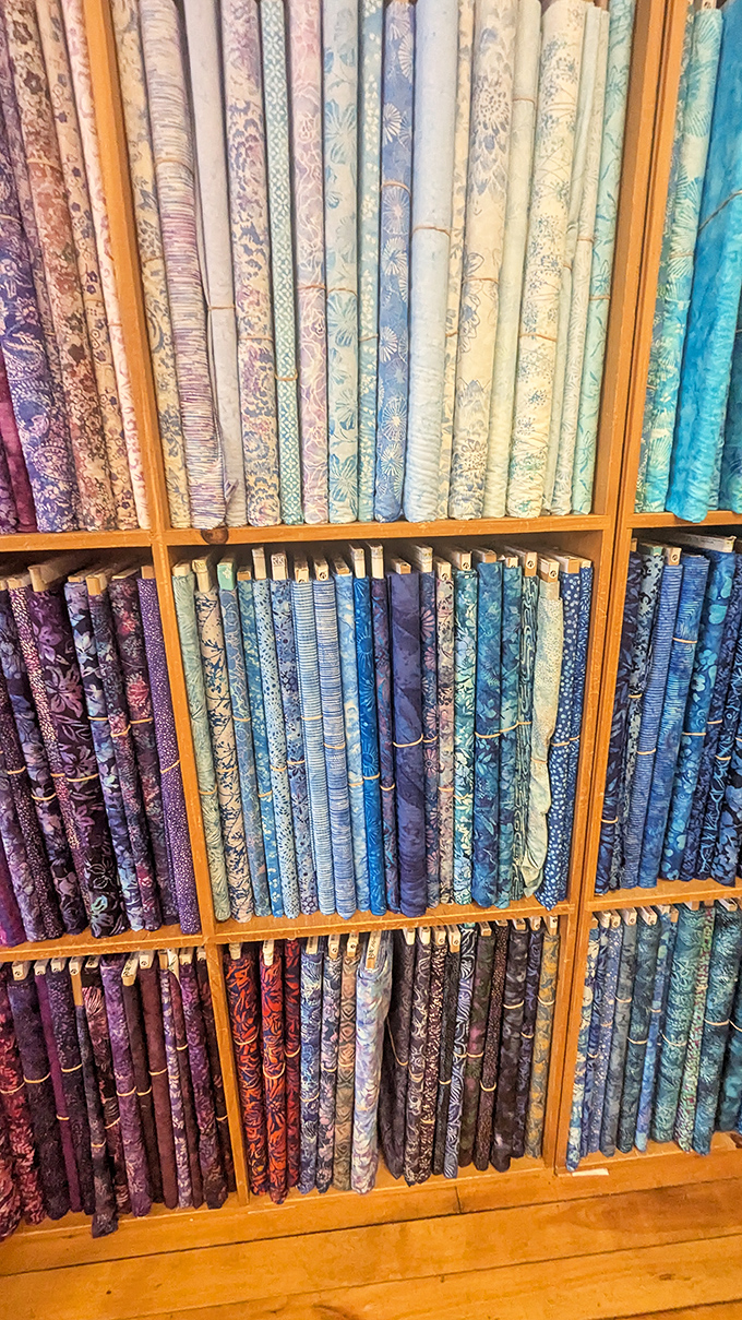 Like a textile library organized by color, these fabric shelves tell stories waiting to be stitched. The blues alone could inspire an ocean of creativity!