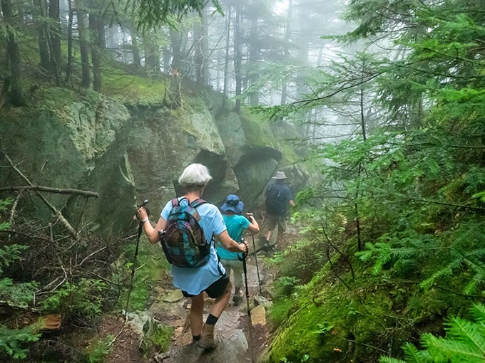 Misty mountain magic hikers navigate Ascutney's rocky paths through ethereal fog, where every step feels like entering another dimension.