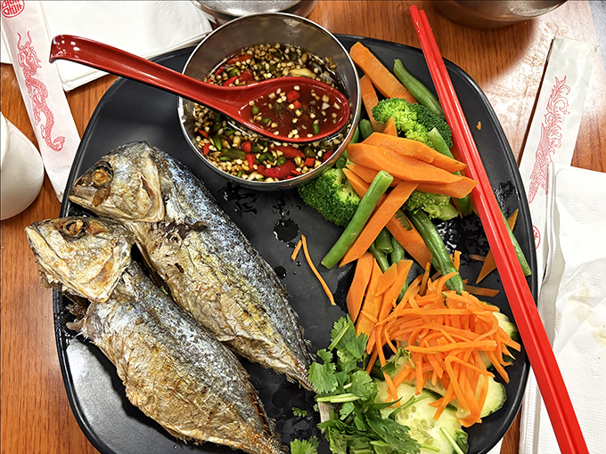 Whole fried mackerel served with fresh vegetables creates a perfect balance of crispy exterior and tender, flaky fish within.