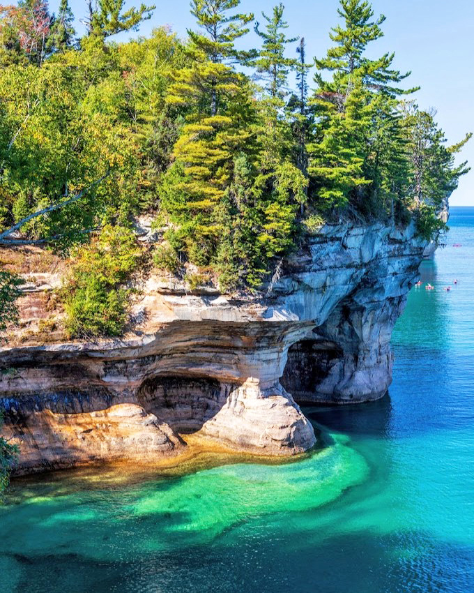 Towering sandstone cliffs stand like nature's skyscrapers, their mineral-painted facades telling geological stories older than any human architecture could dream of being.