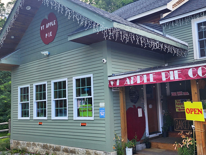 The Vermont Apple Pie Company's green clapboard building with its cheerful red apple sign stands ready to satisfy your pie cravings.