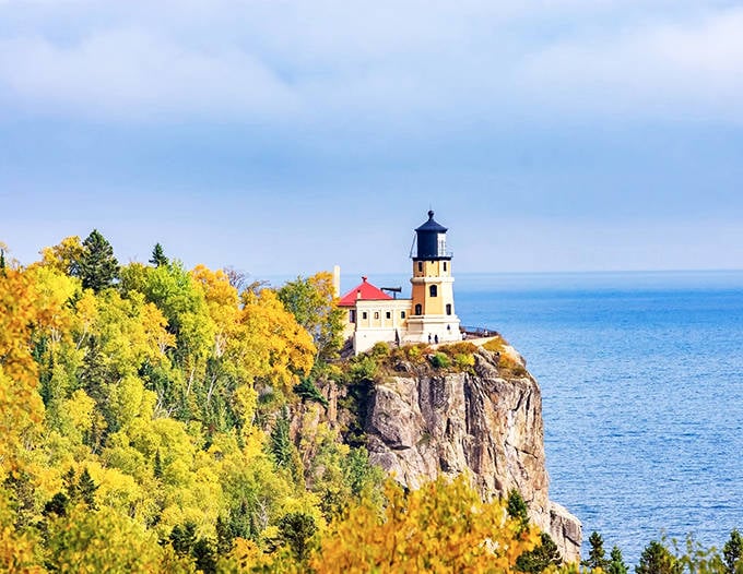 Fall colors frame Split Rock Lighthouse in a golden embrace, showcasing why this historic beacon remains one of Minnesota's most photographed landmarks.