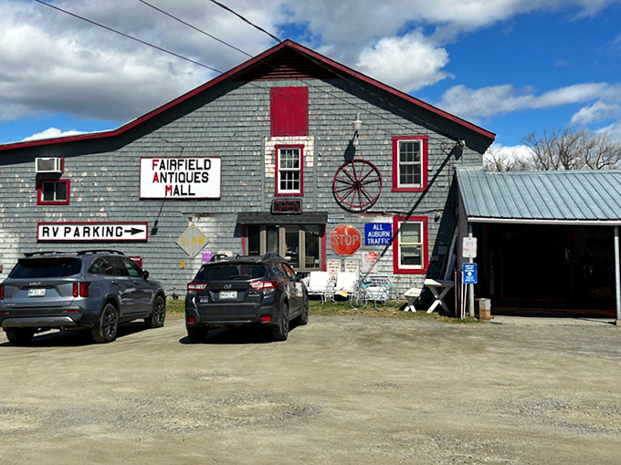 The rustic exterior of Fairfield Antiques Mall with its distinctive gray siding, red trim and vintage wheel decoration, inviting treasure hunters inside.
