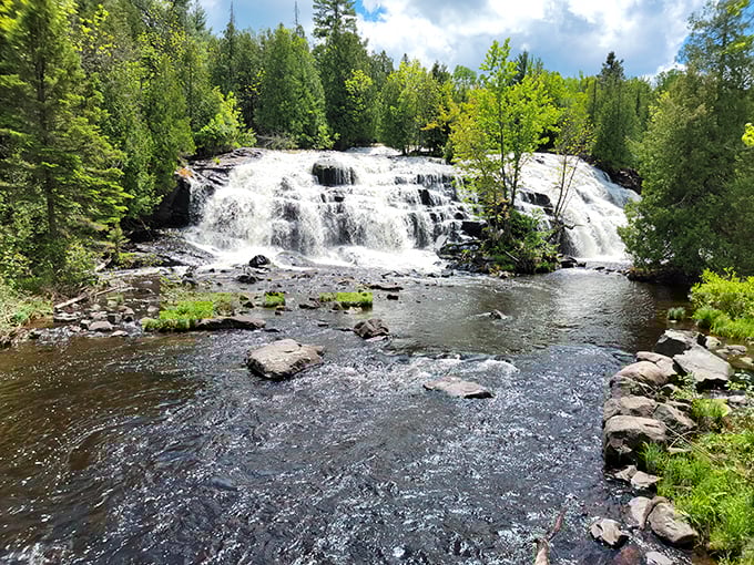 Bond Falls spreads like a white lace fan across the wide rock face, creating dozens of individual cascades that merge into a stunning natural display.
