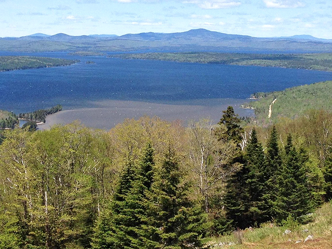 Rangeley Lake spreads like a sapphire mirror beneath mountain sentinels, reflecting Maine's wild beauty in its crystal-clear waters.