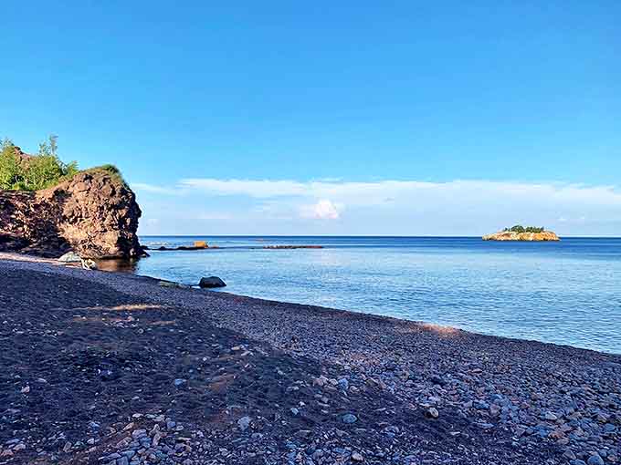 The striking contrast between black sand and blue water creates an otherworldly beach experience unlike any other on the North Shore.
