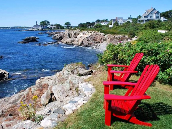 Bright red Adirondack chairs perched on rocky Maine coastline offer the best seats in the house for nature's endless ocean show.