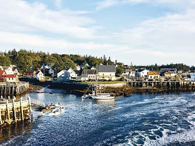 The picturesque waterfront showcases Maine's maritime heritage with boats bobbing in the harbor and American flags fluttering in the sea breeze.