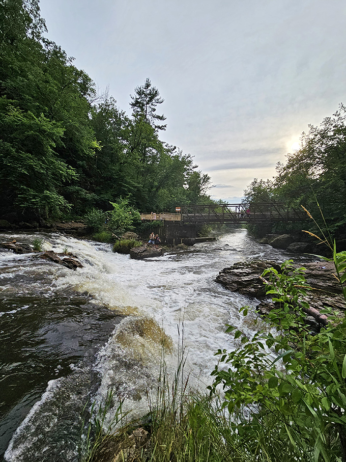 A rustic footbridge spans the rushing waters, offering visitors a front-row seat to nature's power and beauty.