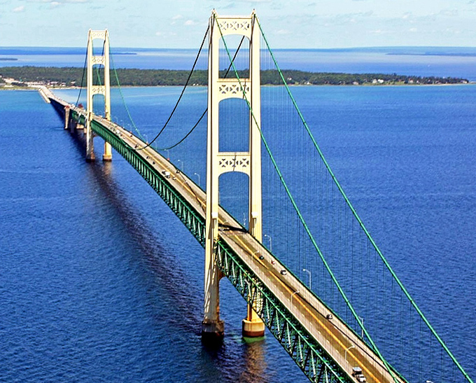 Seen from above, the bridge's ivory towers and emerald span create a striking contrast against the deep blues of Lakes Michigan and Huron.