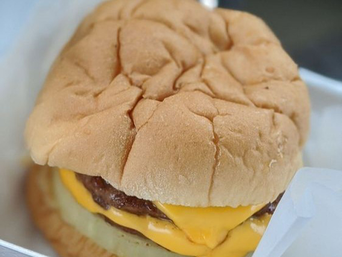 A close-up that explains everything: the perfect cheeseburger with melty American cheese hugging a thin, perfectly caramelized patty.