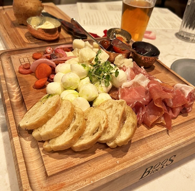 A wooden board becomes an edible canvas of cured meats, artisanal cheeses, and accompaniments that tell stories of tradition and craftsmanship.