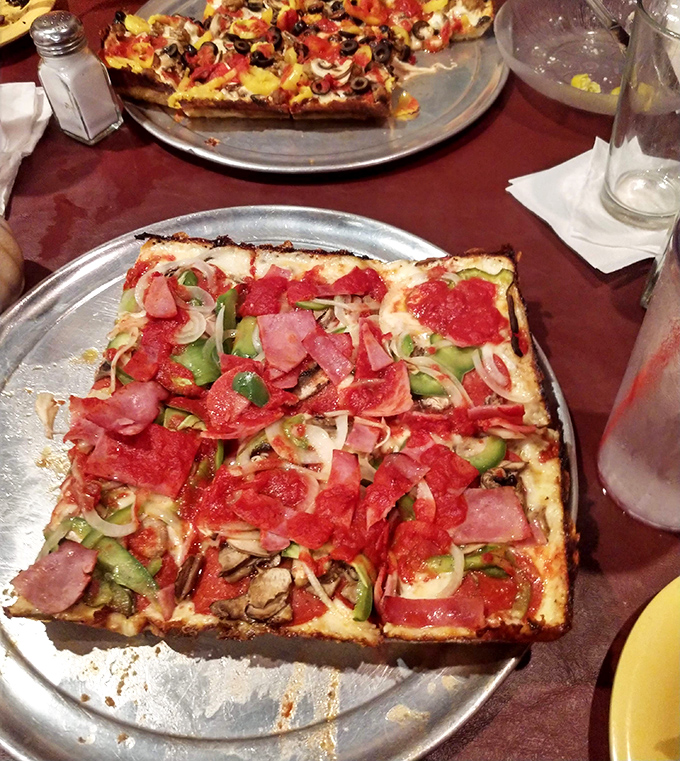 A loaded square masterpiece featuring perfectly arranged toppings – notice how the cheese creates that coveted crispy "frico" edge that Detroit pizza aficionados treasure.
