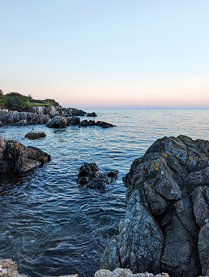 Sunset transforms Colony Beach into a painter's dream, where rocky outcroppings create nature's perfect frame for the Atlantic's evening glow.