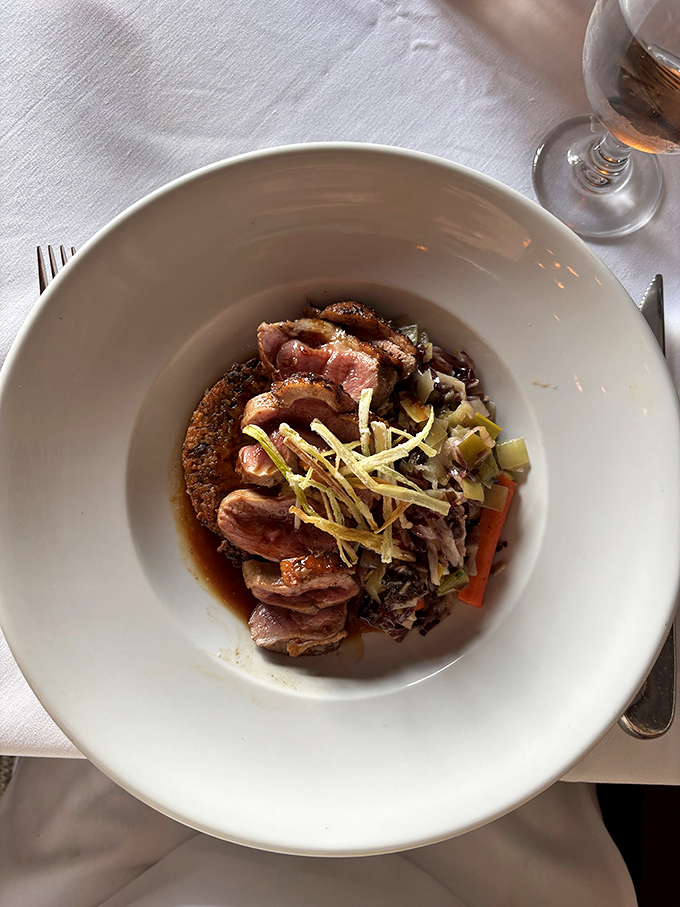 Duck breast with a perfect rose-colored center sits atop colorful vegetables &ndash; proof that fine dining can be both beautiful and satisfying.