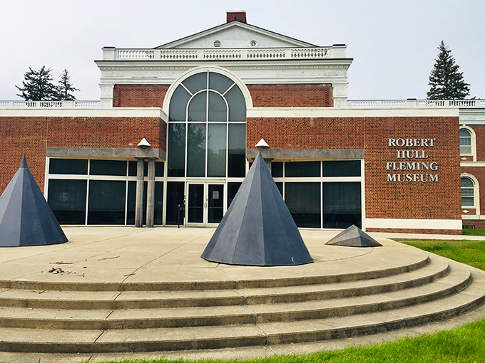 The Fleming Museum's distinctive entrance beckons culture seekers with geometric sculptures that contrast beautifully against the classic brick fa&ccedil;ade.