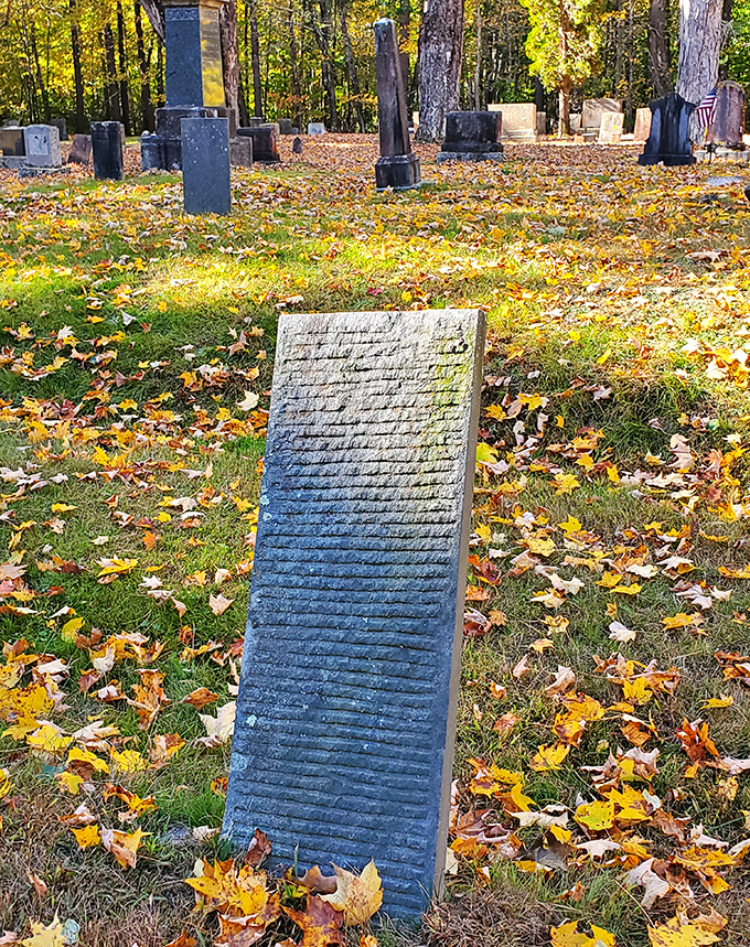 Centuries of New England weather have worn away at this headstone, while nature slowly reclaims what humans have built.