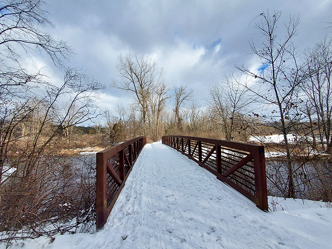 Winter transforms this bridge into a snow-dusted passage between two worlds, where footprints tell tales of explorers braving the Michigan cold.