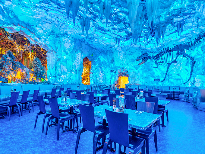 The ice cave dining area glows with ethereal blue light, offering a cool retreat from Florida's heat while fossils seem frozen in time around you.