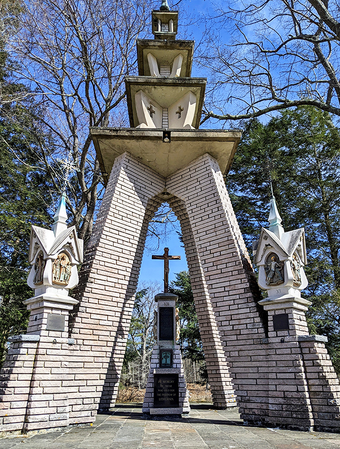 The white monument stands like a sentinel among the trees, its clean lines and religious imagery creating a striking contrast with the natural surroundings.