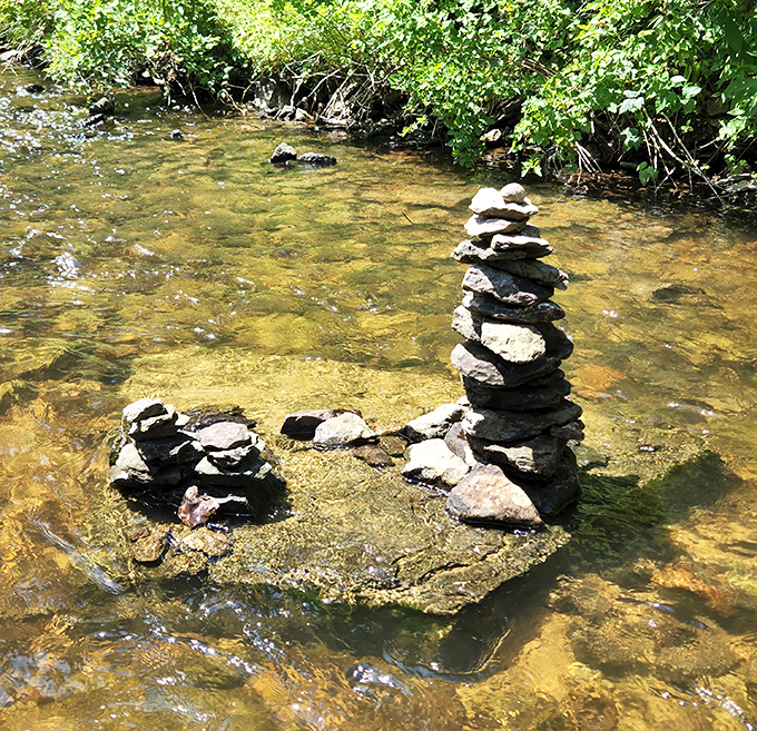 Stone cairns stand like tiny monuments to human creativity, balancing precariously while the river rushes by with indifference.
