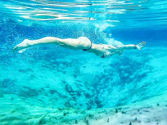 Aquatic ballet: A swimmer glides through underwater clarity that would make Caribbean resorts jealous, suspended between sky and sandy bottom.