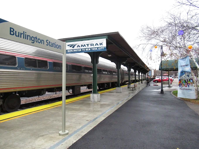 The Amtrak Vermonter pulls into the station, its distinctive red, white and blue livery standing out against Vermont's natural landscape.