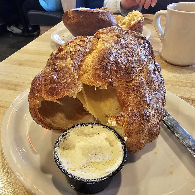 The legendary popover arrives like a golden cloud, waiting to be slathered with honey butter that melts into every warm, airy pocket.