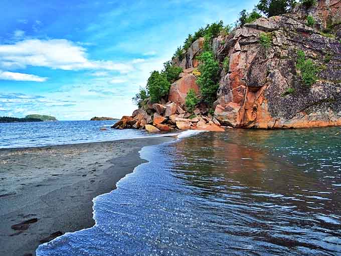 Black Beach surprises with its dark volcanic sand and striking red rock formations along Lake Superior's edge.