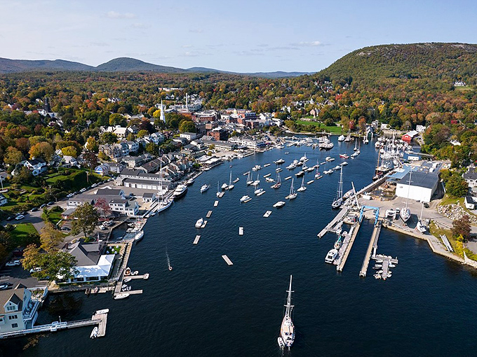 Camden Harbor sparkles under clear skies, with mountains rising dramatically behind the town's picture-perfect waterfront.
