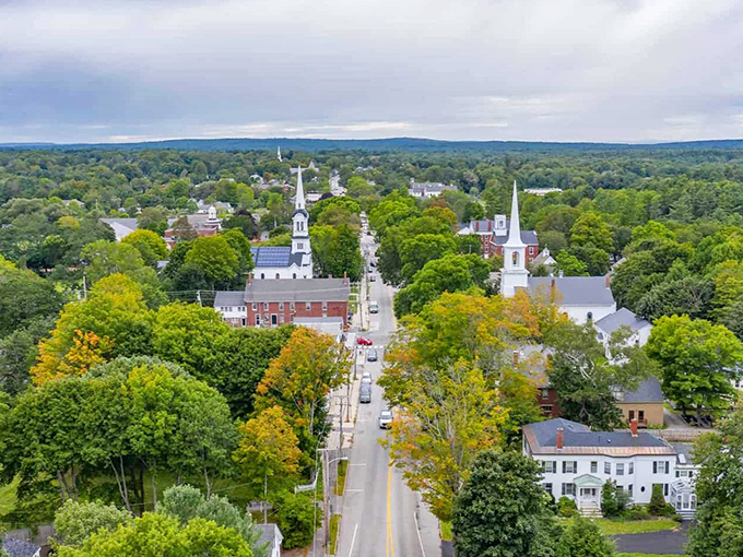 White church steeples punctuate the green canopy like architectural exclamation points in this bird's-eye view of classic New England charm.