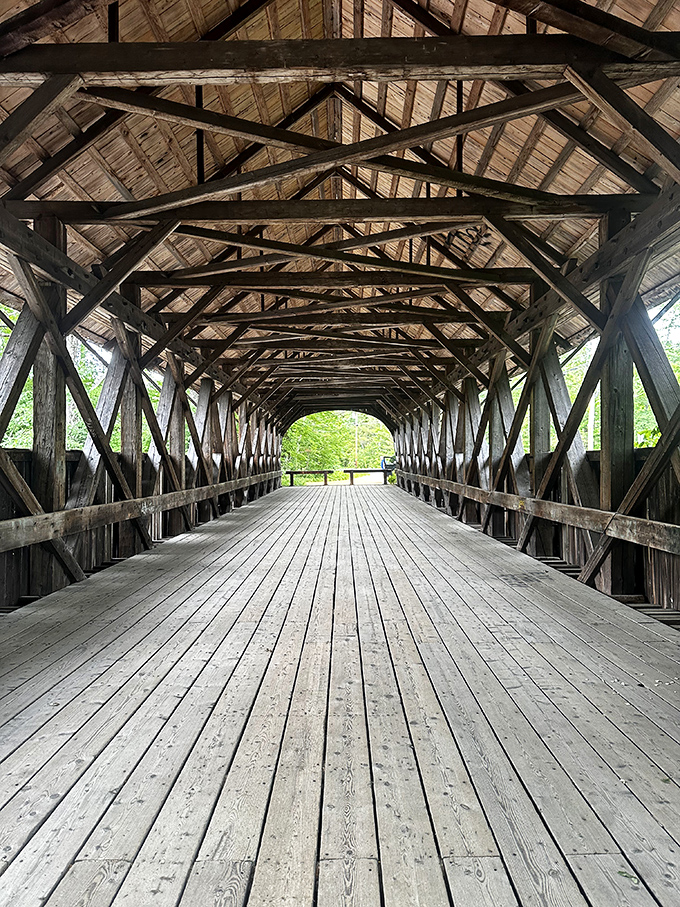The intricate wooden trusses of Sunday River Bridge create a geometric masterpiece overhead, a cathedral of craftsmanship in the woods.