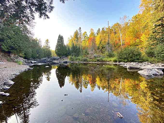 A perfect campsite awaits beside still waters, complete with fire ring and log seating for evening stories beneath star-filled northern skies.