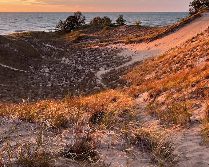 Baldtop Dune catches the sunset's glow, its windswept grasses transformed into copper threads against the darkening sky.