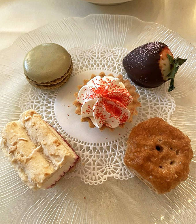 A dessert plate that's practically a work of art &ndash; featuring a delicate macaron, chocolate-dipped strawberry, cream-topped tart, and what appears to be homemade ice cream sandwich.