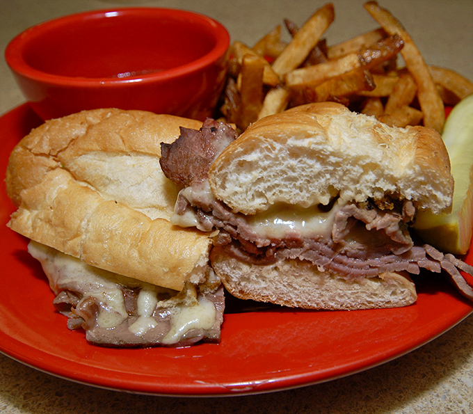 Thinly sliced roast beef piled high on a soft roll with melted cheese &ndash; a savory masterpiece waiting to be dipped in rich au jus.