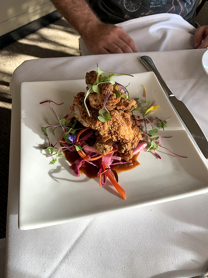 Crispy fried quail perches atop a colorful medley of pickled vegetables &ndash; comfort food elevated to art form with playful presentation.