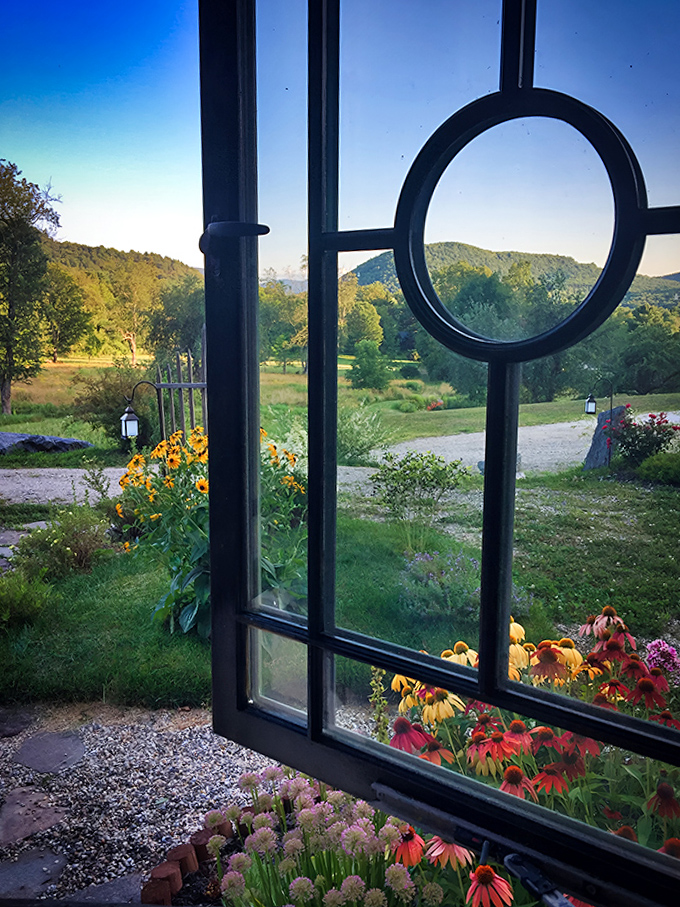 A glimpse through the window reveals colorful gardens that would make any hobbit gardener proud of this Vermont hideaway.