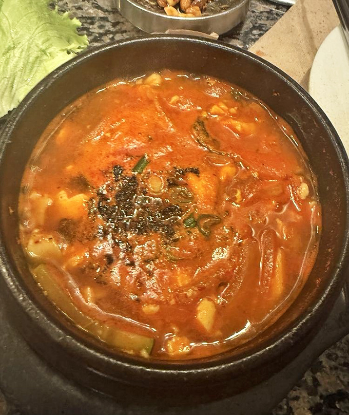 Kimchi-jjigae bubbles like a cauldron of comfort, the fermented kimchi providing depth while tender pork and silken tofu absorb the rich, spicy broth.