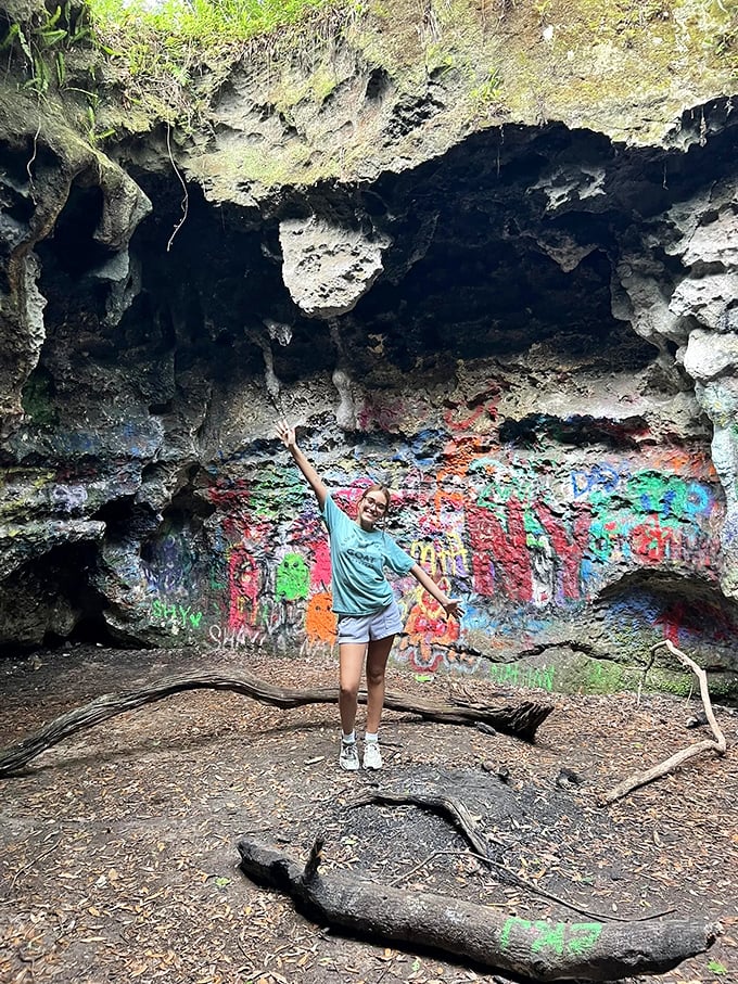 Young adventurers strike playful poses against the graffiti-adorned cave walls, where human expression meets geological wonder in vibrant contrast.