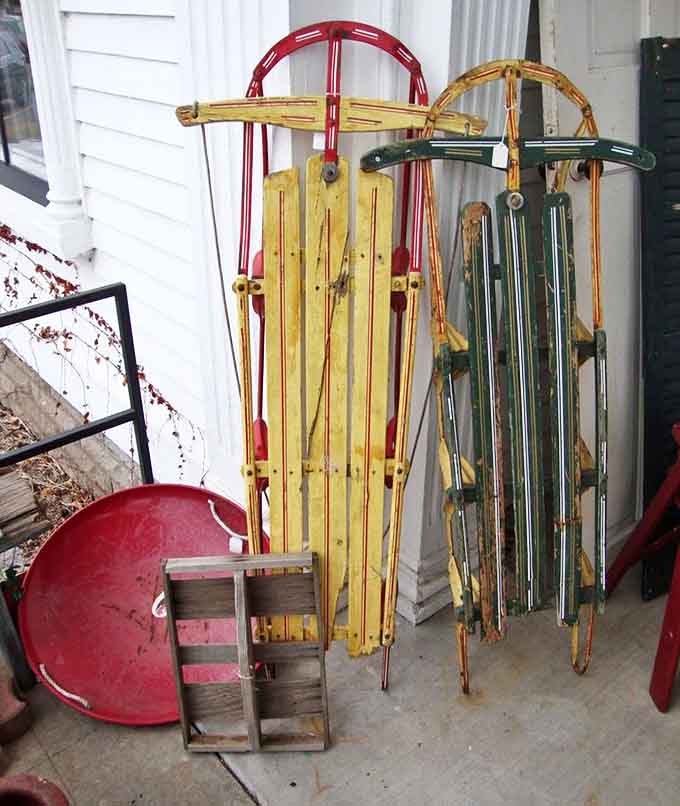 Vintage wooden sleds in vibrant reds, yellows, and greens stand ready for Minnesota winters or charming wall displays.