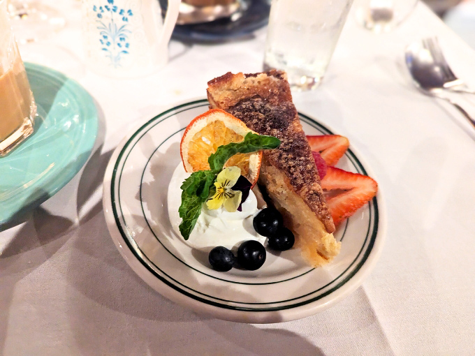 A perfect slice of something sweet, garnished with fresh berries and a delicate orange slice &ndash; proof that dessert is serious business here.