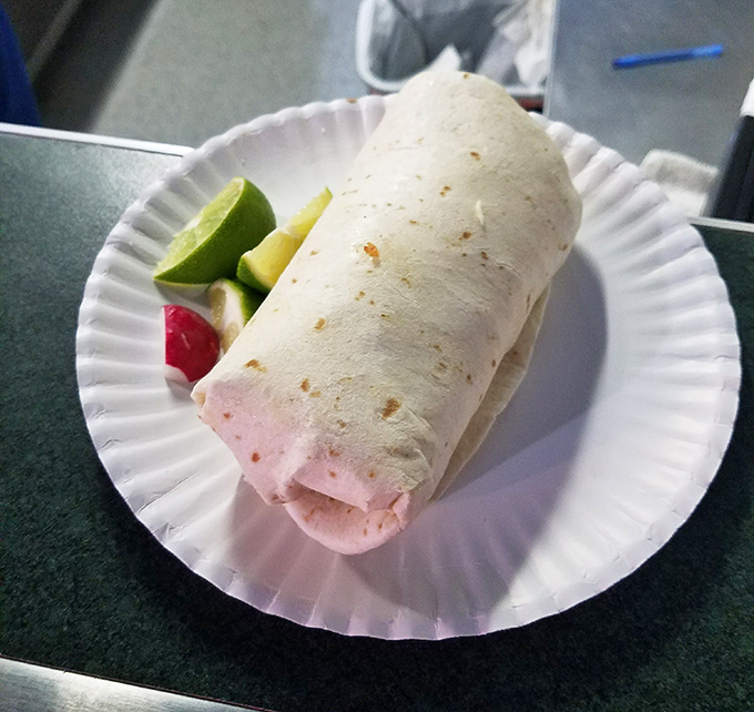 A perfectly wrapped burrito awaits its destiny, accompanied by lime wedges that add that crucial bright finish to every bite.