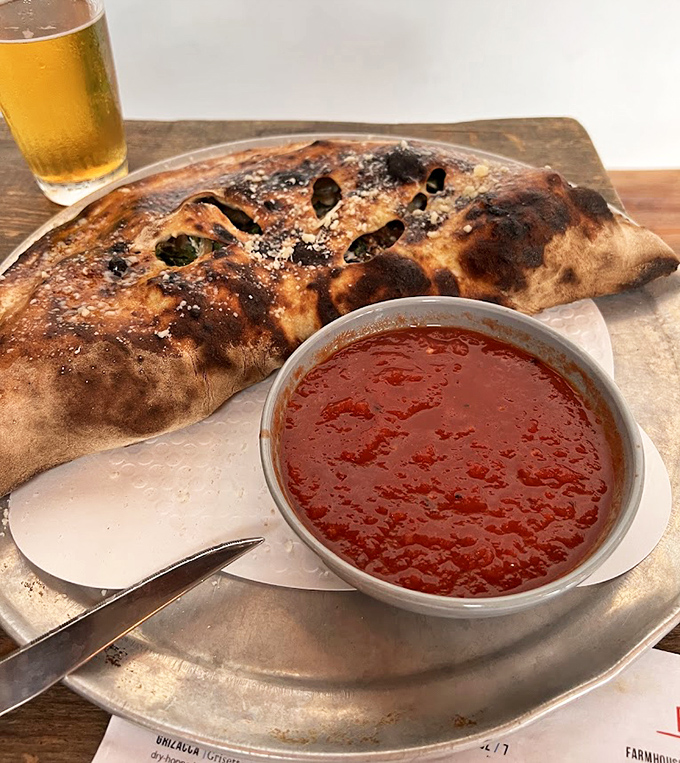 The calzone arrives like a gift &ndash; golden-brown exterior hiding a treasure trove of fillings, with marinara sauce for dunking between bites.