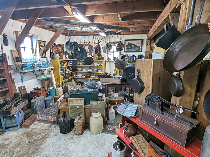 Kitchen artifacts from bygone eras hang from rustic beams, each cast iron pan and enamel pot holding memories of family meals and simpler times.