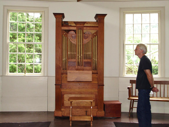 The antique pipe organ stands ready to fill the space with music, its wooden case as much a work of art as the instrument inside.