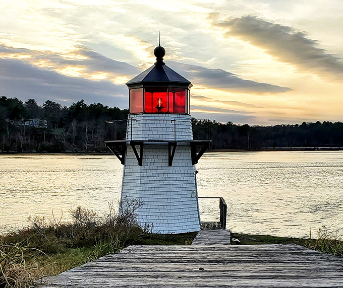 As evening approaches, the lighthouse's red beacon glows warmly against the twilight sky, a sailor's guiding friend.